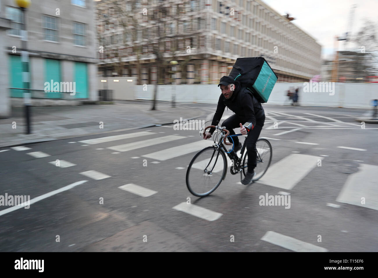 Deliveroo cycle rider giving thumbs up as he delivers hot food to ...