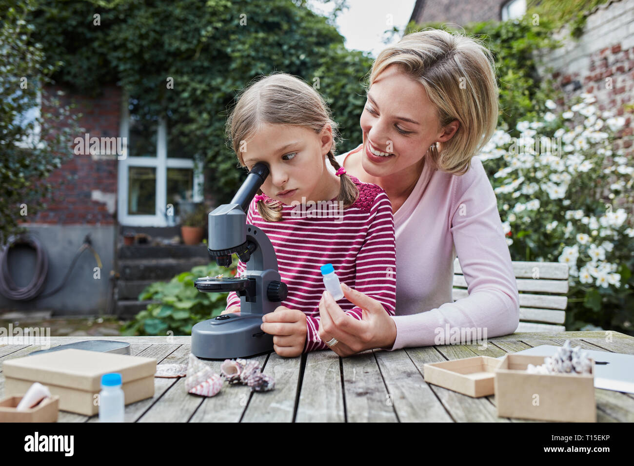 Mother and daughter using microscope together at garden table Stock ...