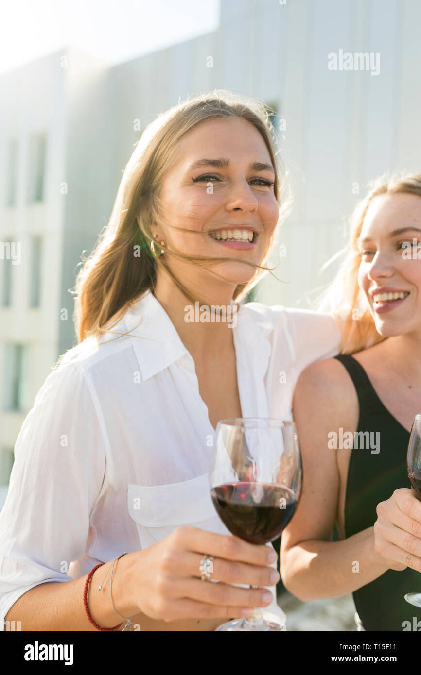 Girlfriends on a rooftop terrace, having fun by the pool, drinking red ...