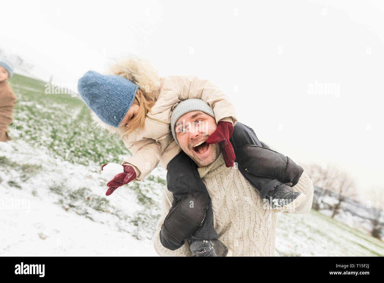 Playful father carrying daughter piggyback in winter landscape Stock ...