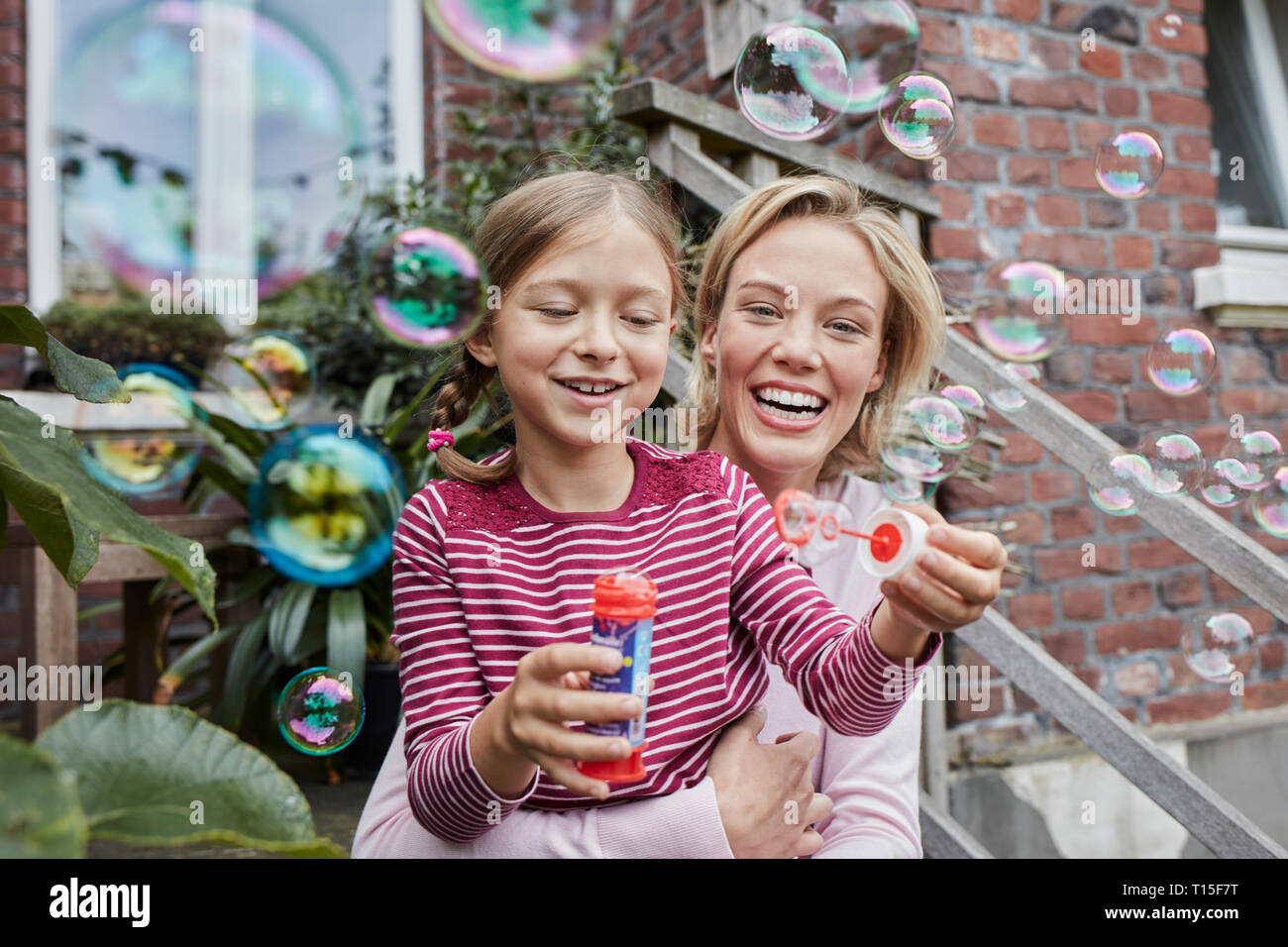 Happy mother and daughter making soap bubbles Stock Photo - Alamy
