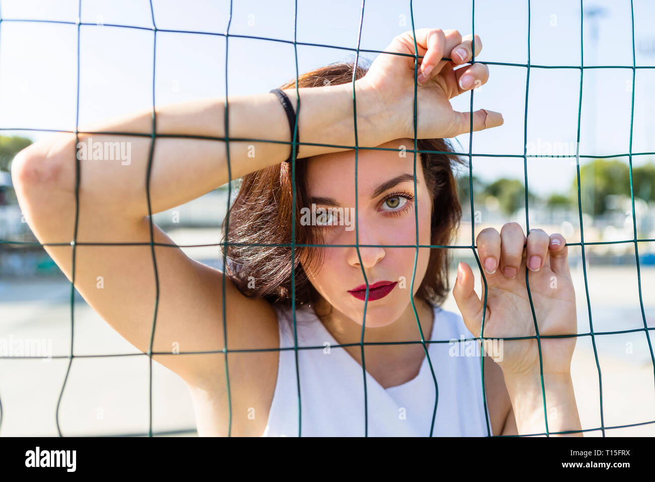 Portrait of young woman behind fence Stock Photo - Alamy
