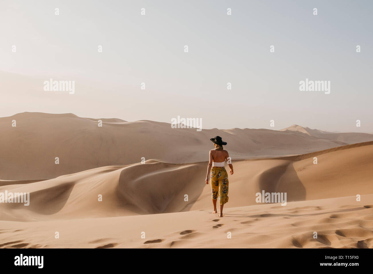 Namibia, Namib, back view of woman walking barefoot on desert dune ...