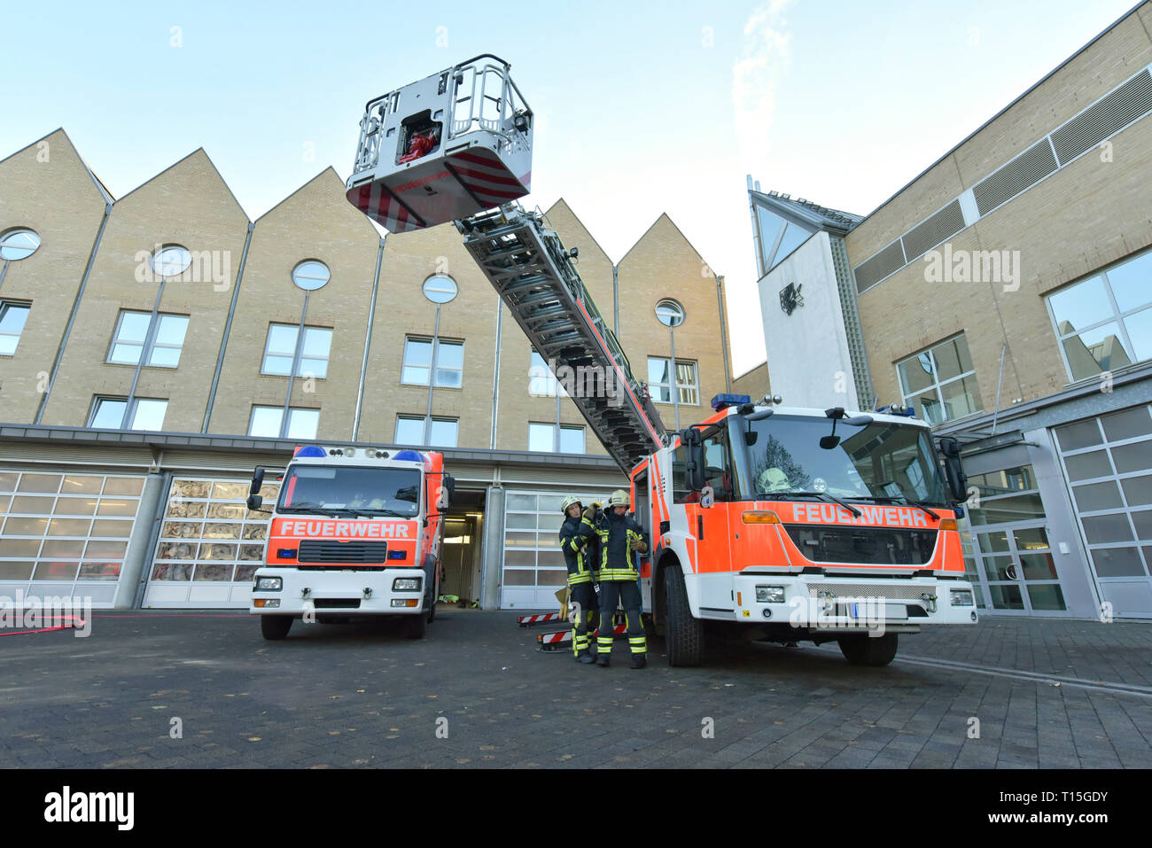 Two firefighters standing on yard at fire engine preparing for an ...