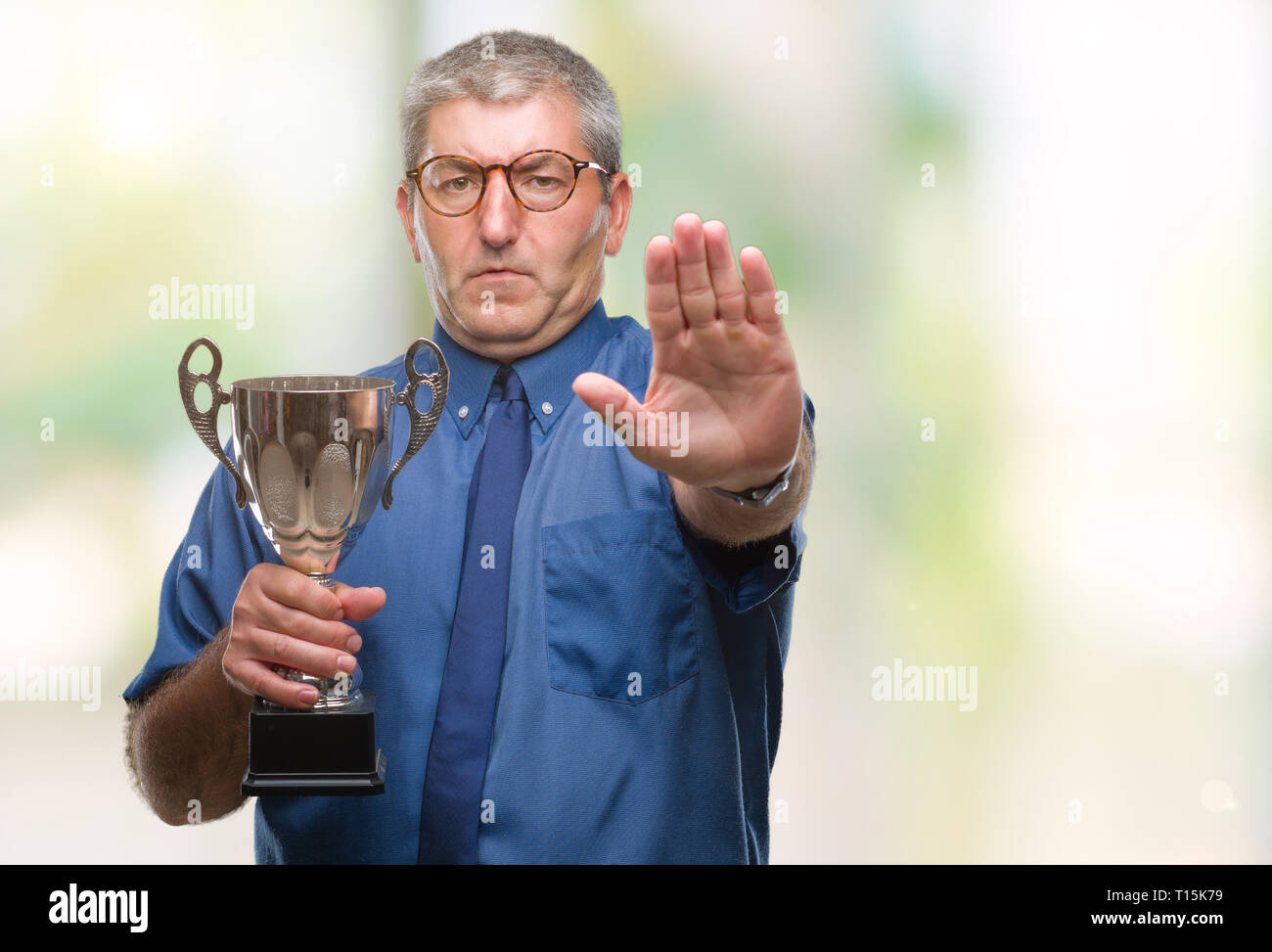 Handsome senior successful man holding trophy over isolated background ...