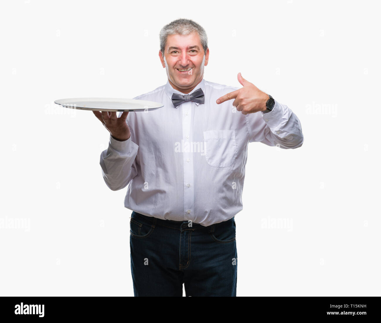 Handsome senior waiter man holding silver tray over isolated background ...