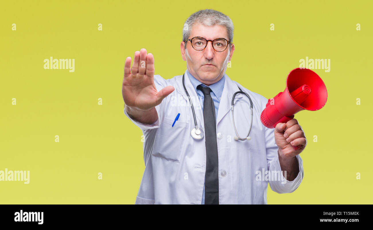 Handsome senior doctor man yelling through megaphone over isolated ...