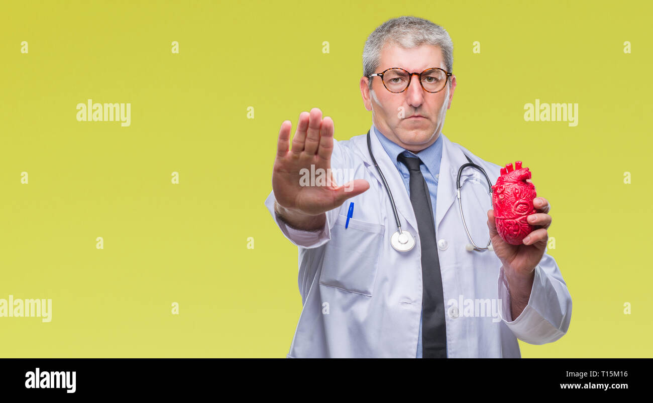 Handsome senior cardiologist doctor man holding heart over isolated ...