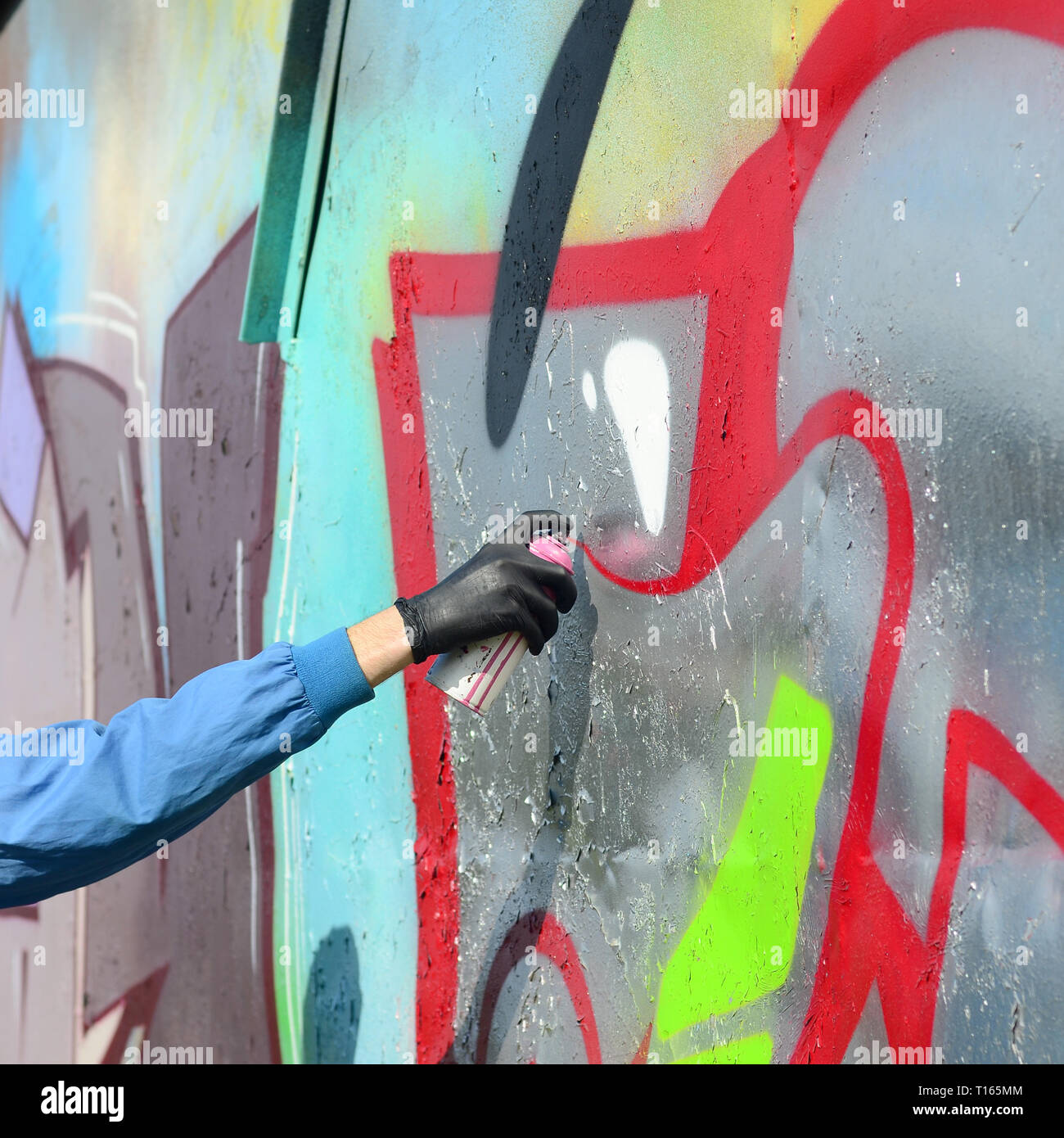 A hand with a spray can that draws a new graffiti on the wall. Photo of ...