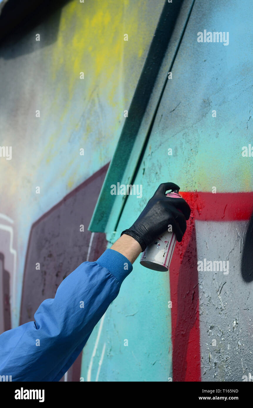 A hand with a spray can that draws a new graffiti on the wall. Photo of ...