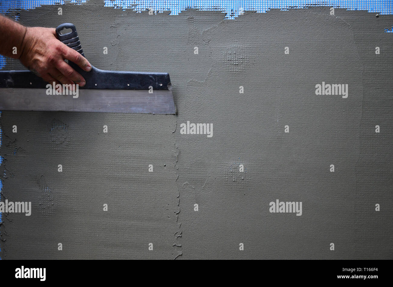 Hands of an old manual worker with wall plastering tools renovating ...