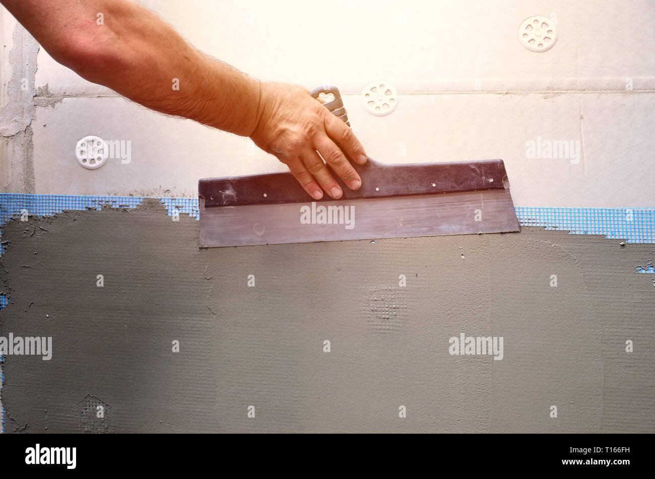 Hands of an old manual worker with wall plastering tools renovating ...