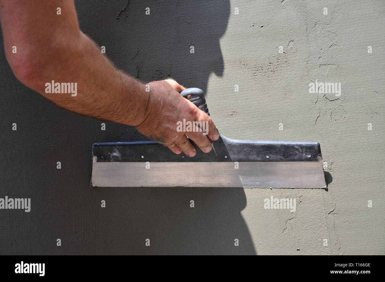 Hands of an old manual worker with wall plastering tools renovating ...