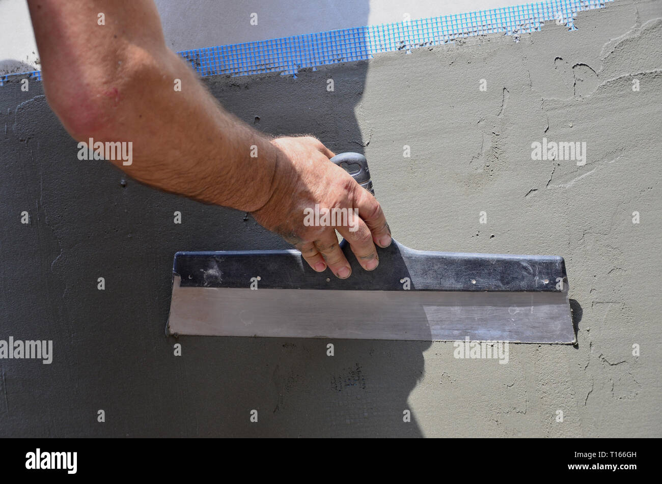 Hands of an old manual worker with wall plastering tools renovating ...