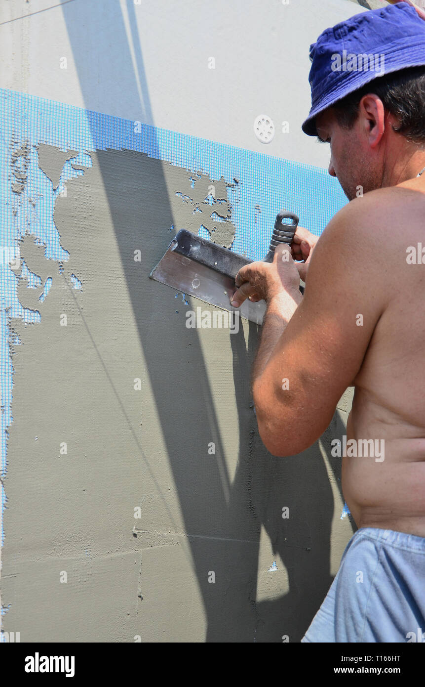 Fifty years old manual worker with wall plastering tools renovating ...