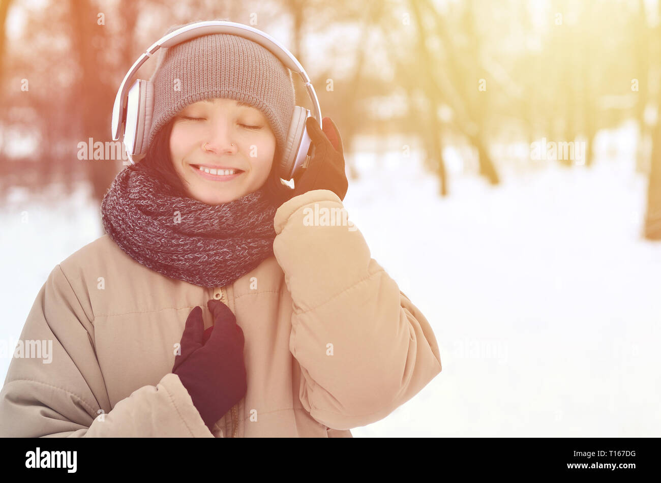 Pretty young girl wear warm winter earmuffs and scarf. Fun brunette ...