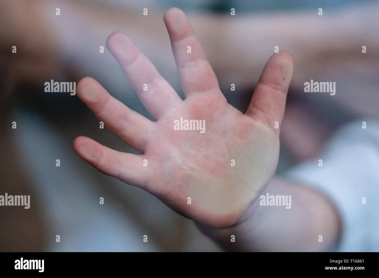 The child's small hand is pressed against the window glass with ...