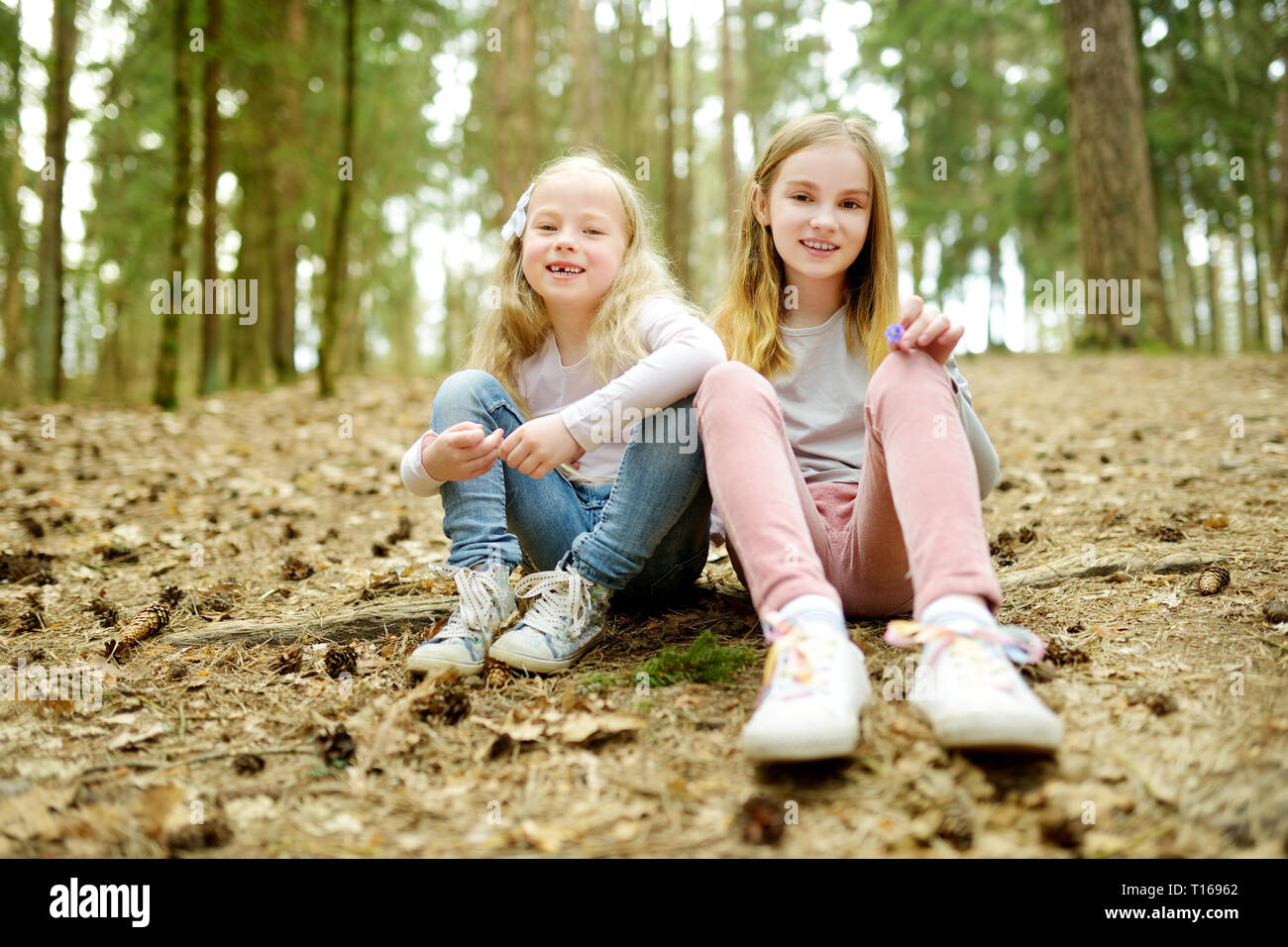 Two cute young sisters having fun during forest hike on beautiful early ...