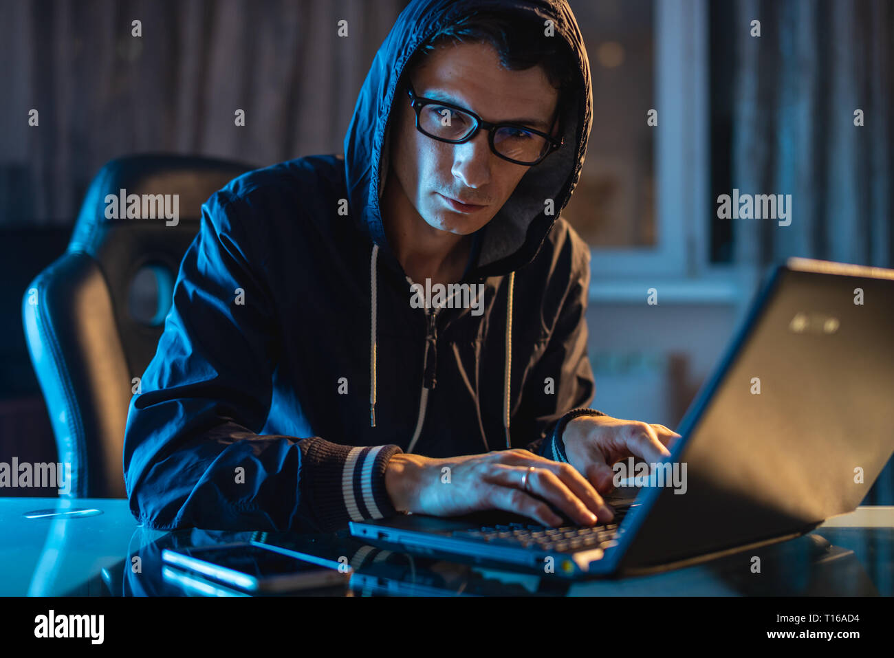Man in the hood looking in the camera. Hacker attacks and stealing ...
