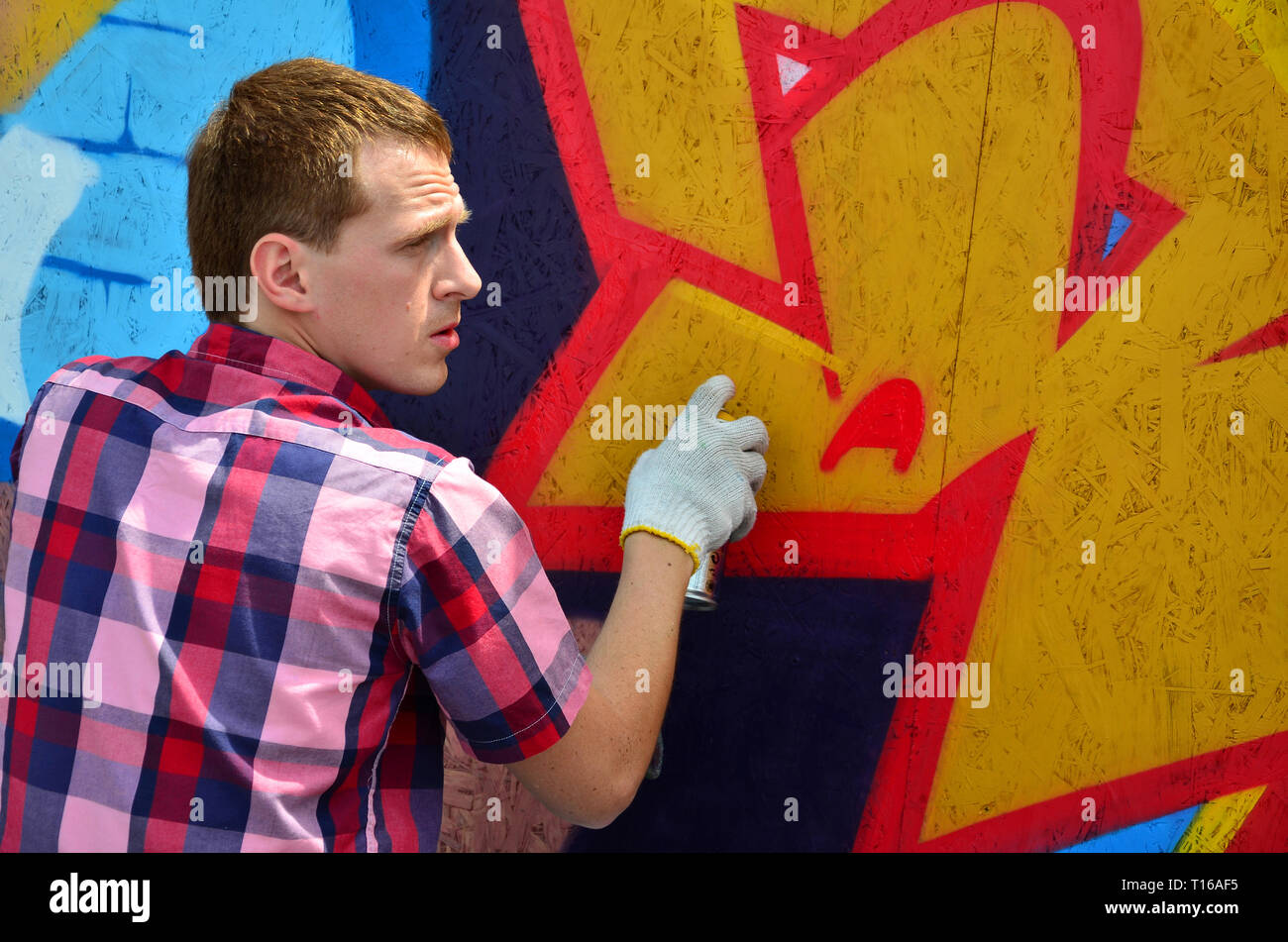A young red-haired graffiti artist paints a new graffiti on the wall ...