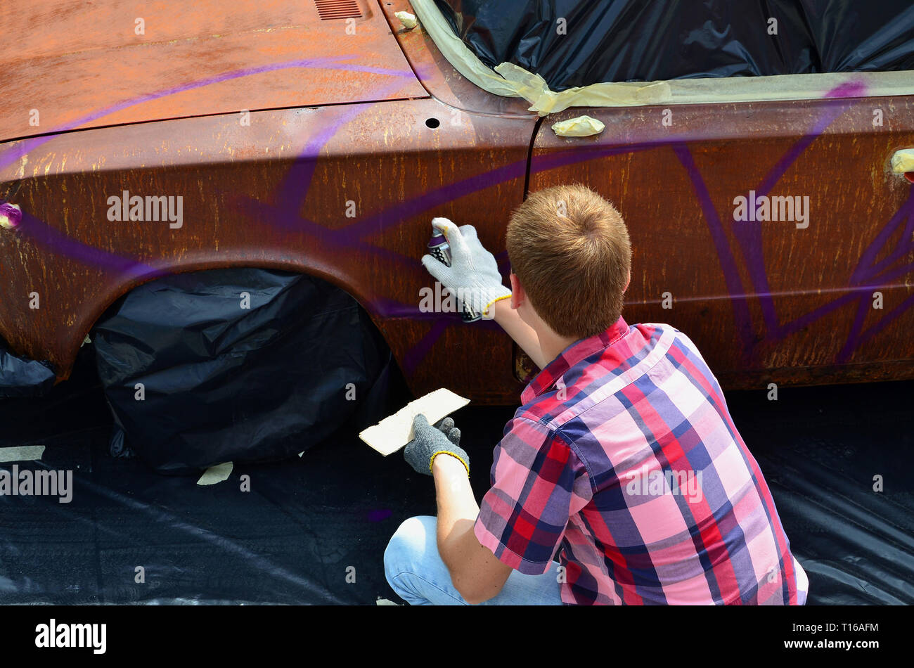 A young red-haired graffiti artist paints a new colorful graffiti on ...