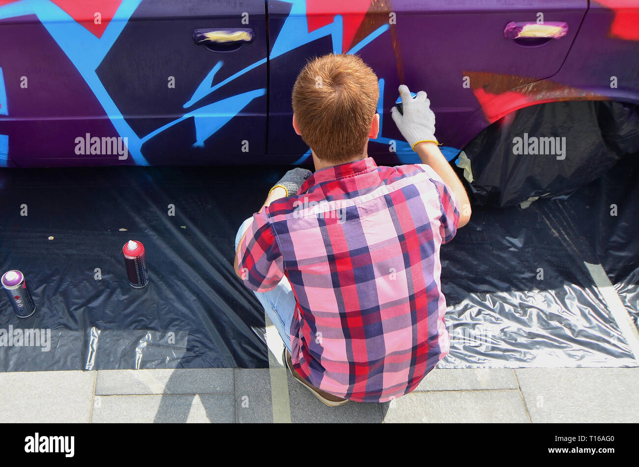 A young red-haired graffiti artist paints a new colorful graffiti on ...