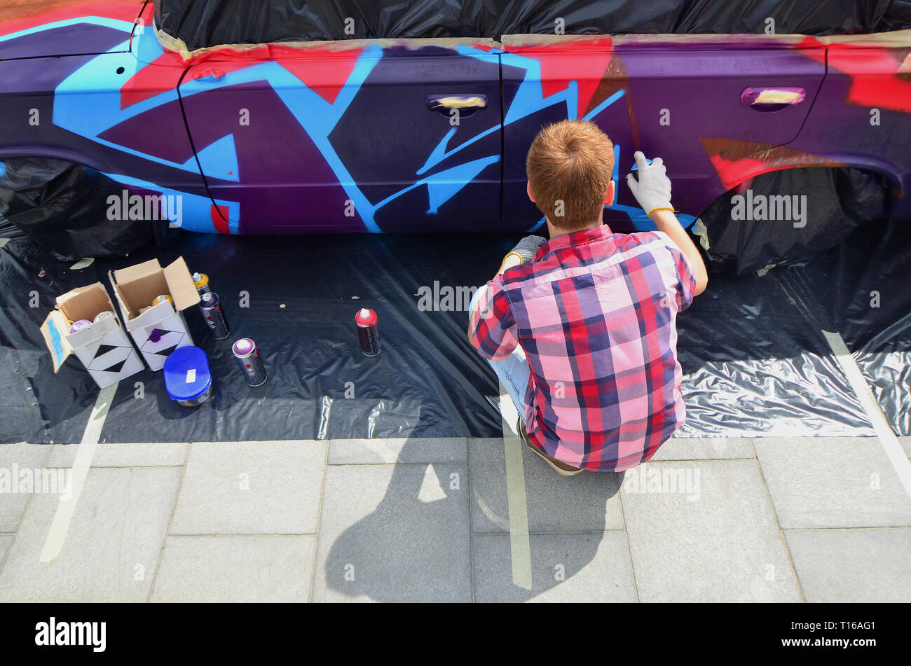 A young red-haired graffiti artist paints a new colorful graffiti on ...