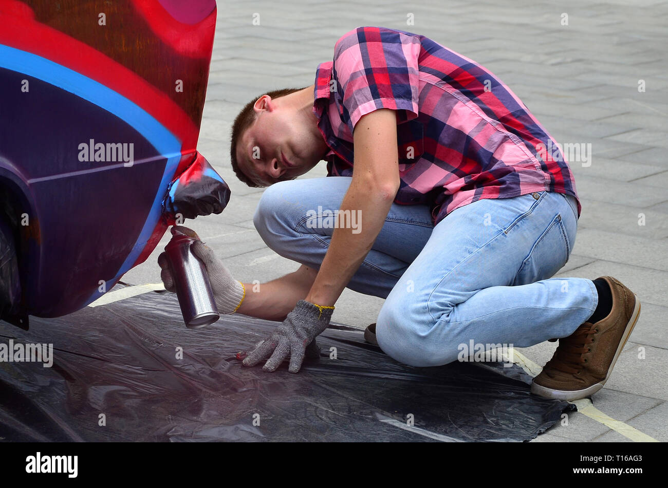 A young red-haired graffiti artist paints a new colorful graffiti on ...