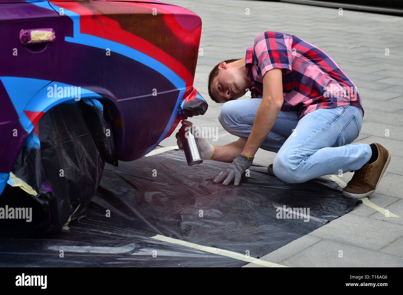 A young red-haired graffiti artist paints a new colorful graffiti on ...