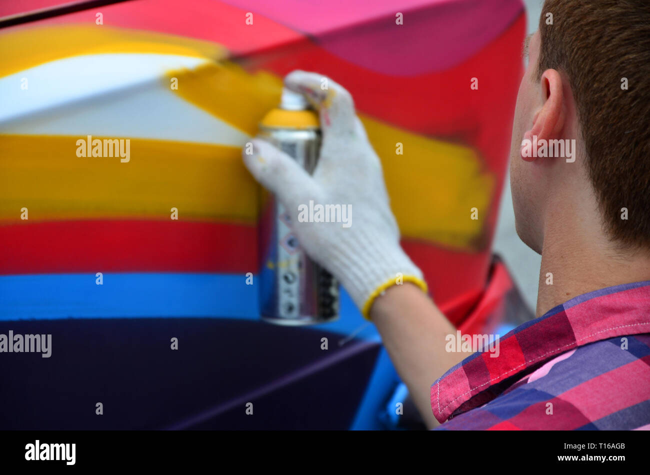 A young red-haired graffiti artist paints a new colorful graffiti on ...