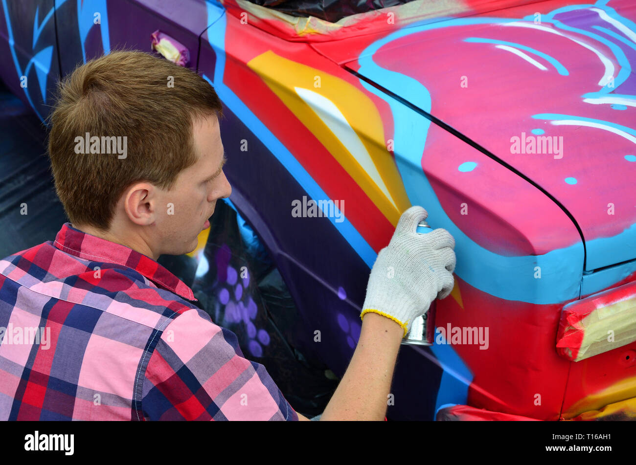 A young red-haired graffiti artist paints a new colorful graffiti on ...