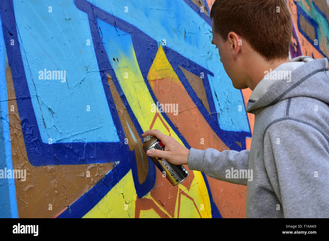 A young red-haired graffiti artist paints a new graffiti on the wall ...