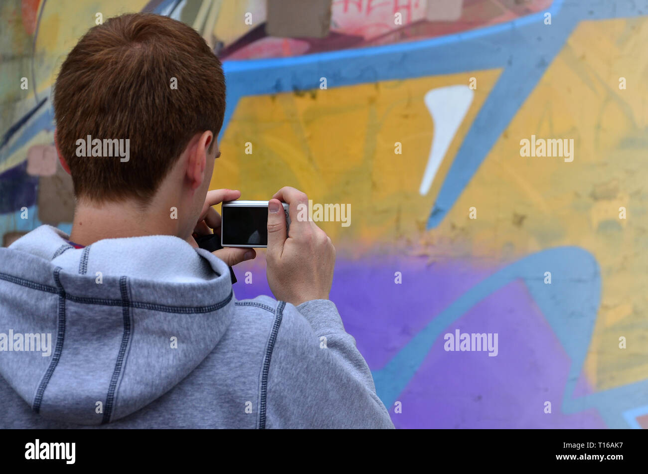 A young graffiti artist photographs his completed picture on the wall ...