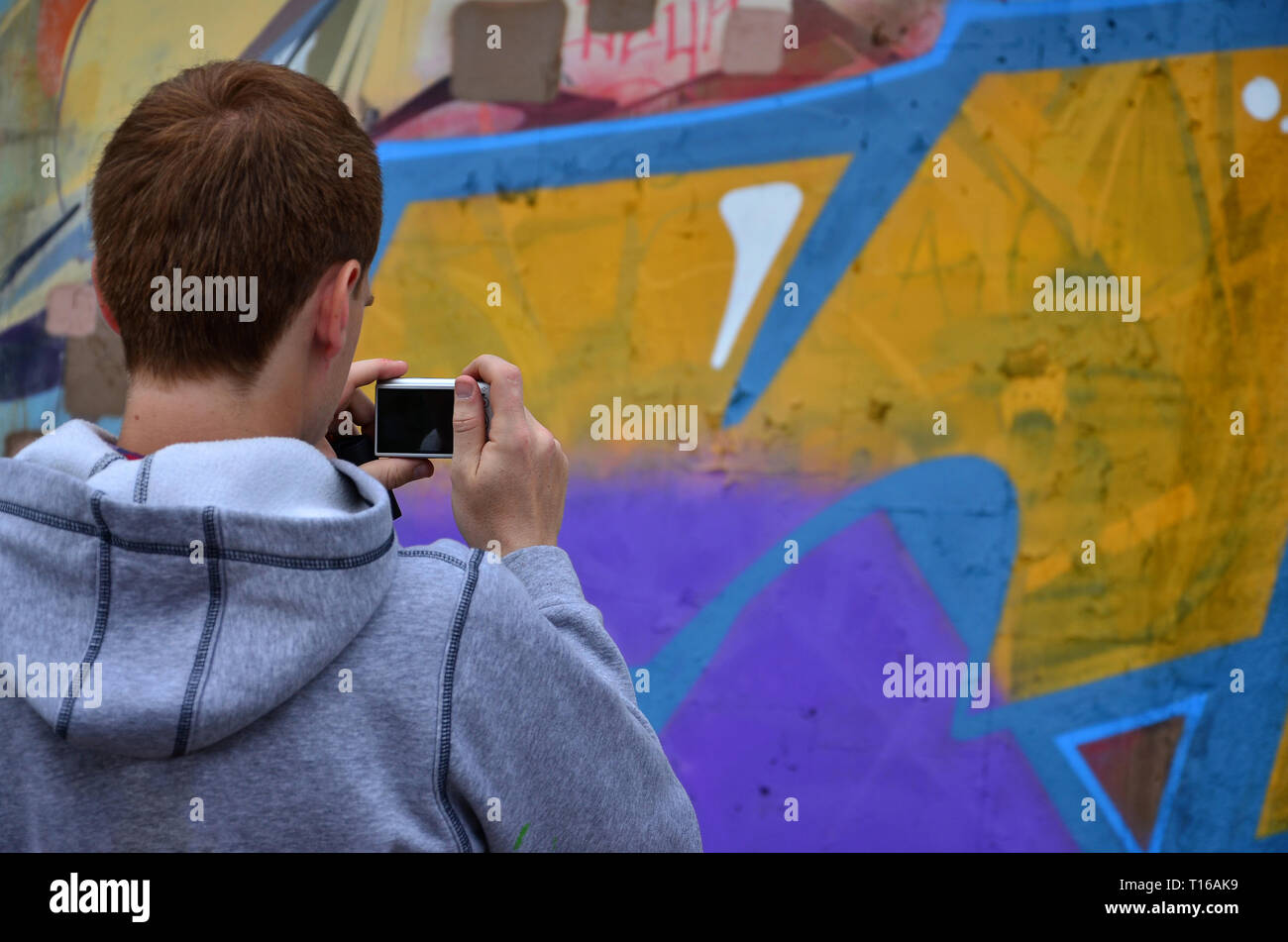 A young graffiti artist photographs his completed picture on the wall ...