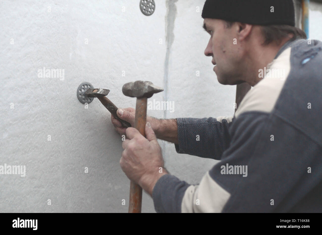 An elderly workman clogs a dowel into a plastic umbrella mount in a ...