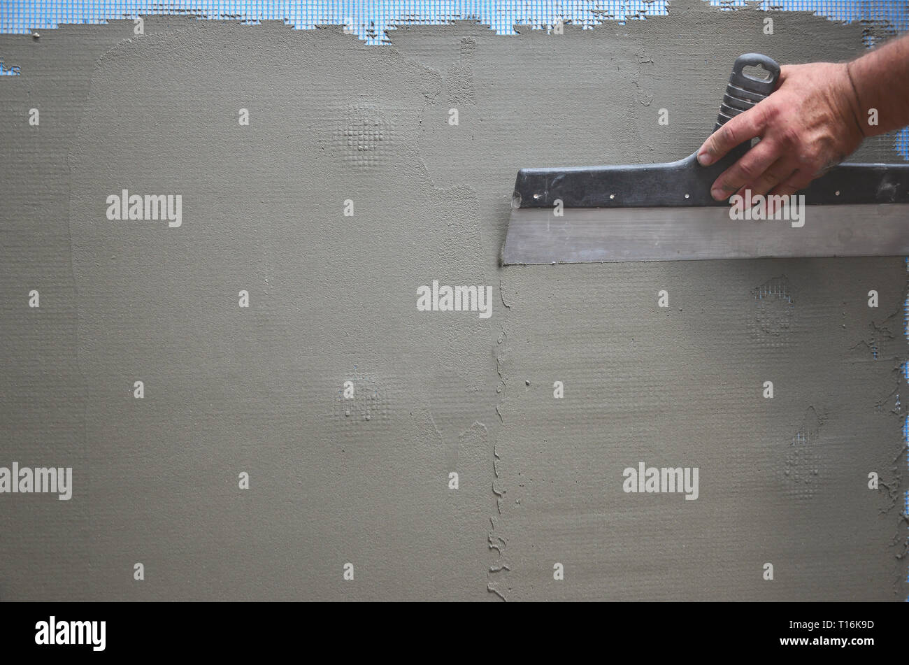 Hands of an old manual worker with wall plastering tools renovating ...