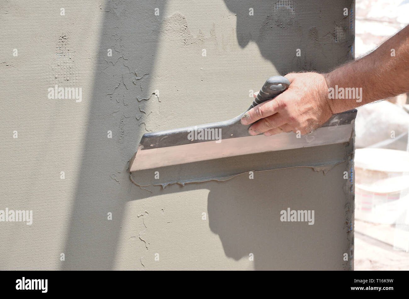 Hands of an old manual worker with wall plastering tools renovating ...