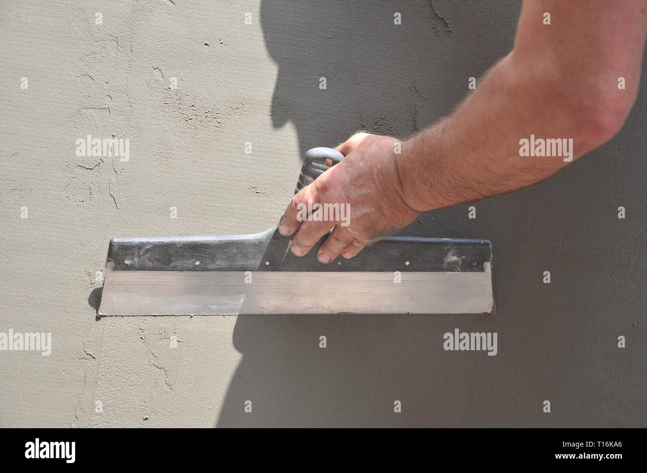 Hands of an old manual worker with wall plastering tools renovating ...