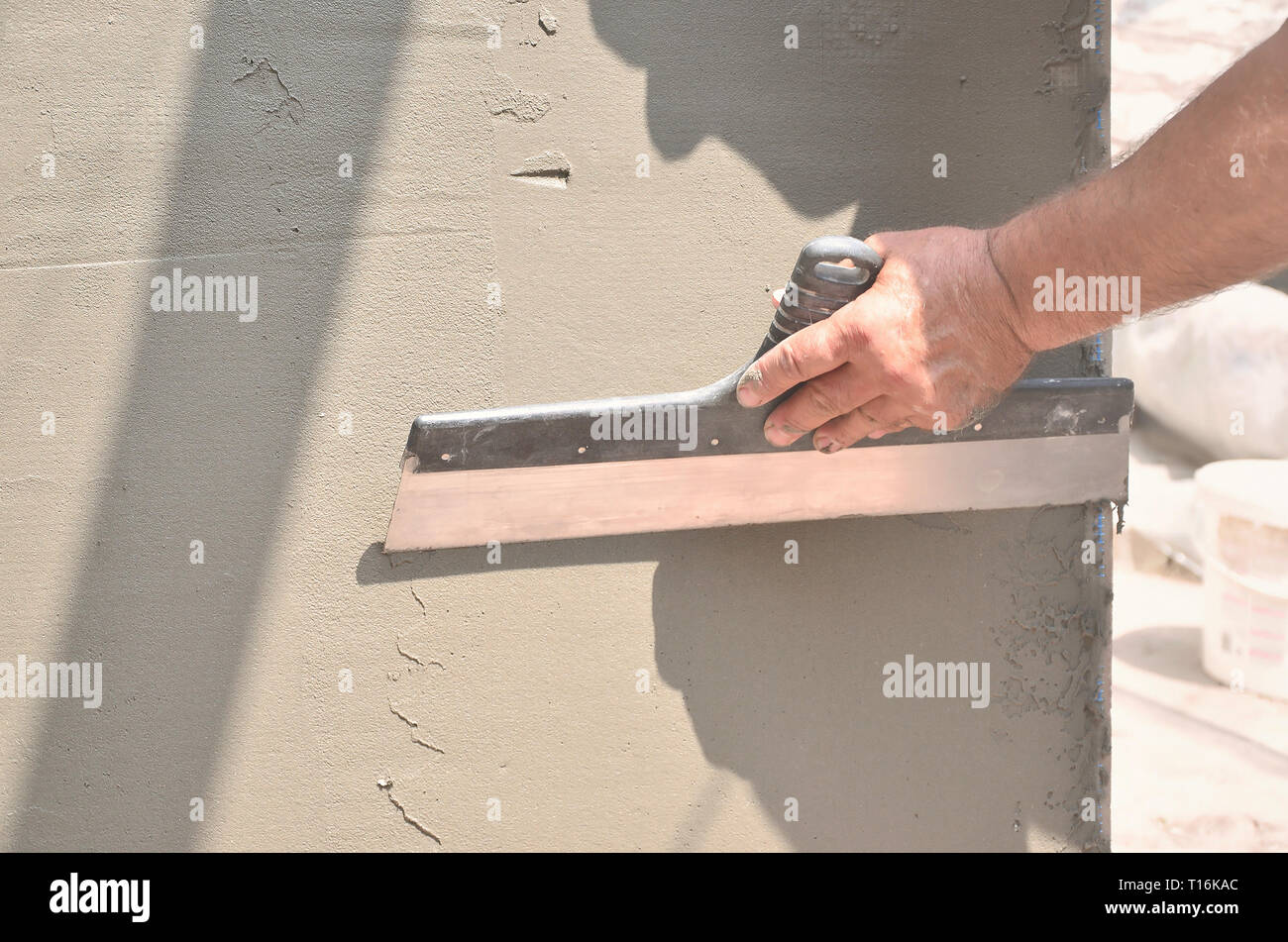Hands of an old manual worker with wall plastering tools renovating ...
