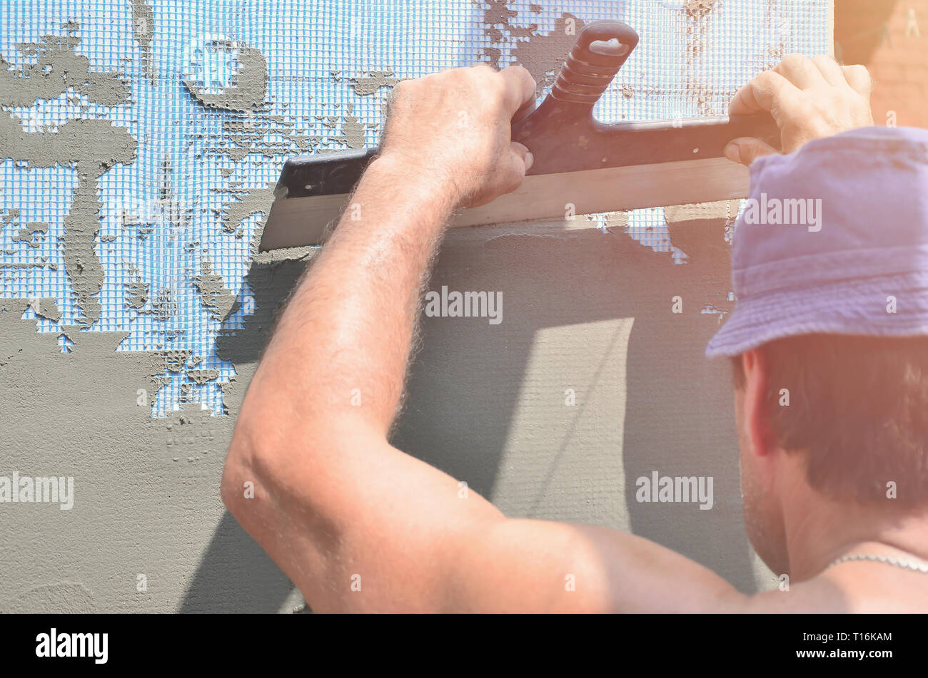 Fifty years old manual worker with wall plastering tools renovating ...