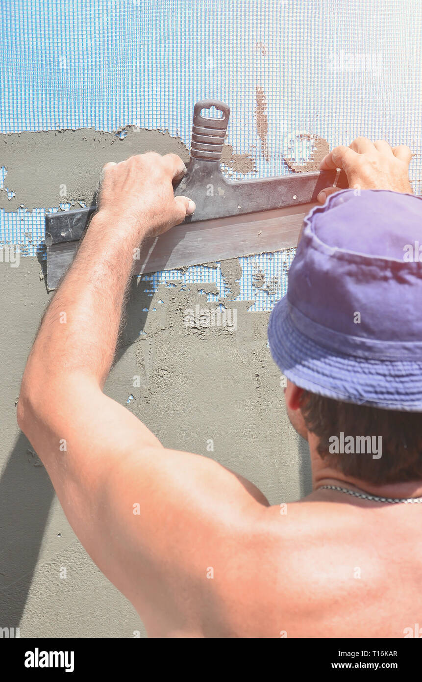 Fifty years old manual worker with wall plastering tools renovating ...
