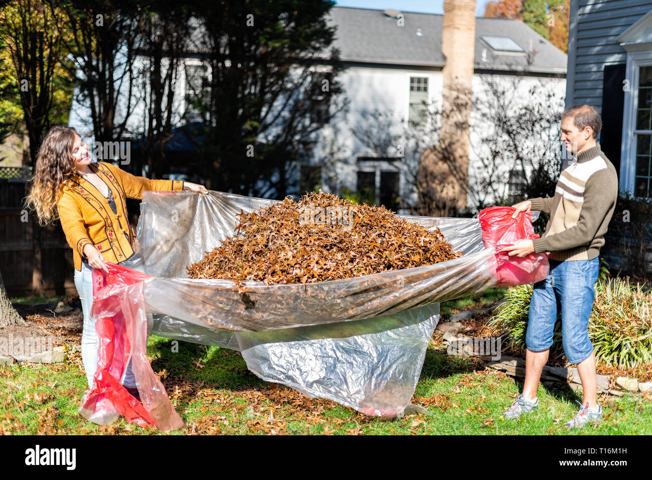 Young happy man and woman couple homeowner in garden front yard ...