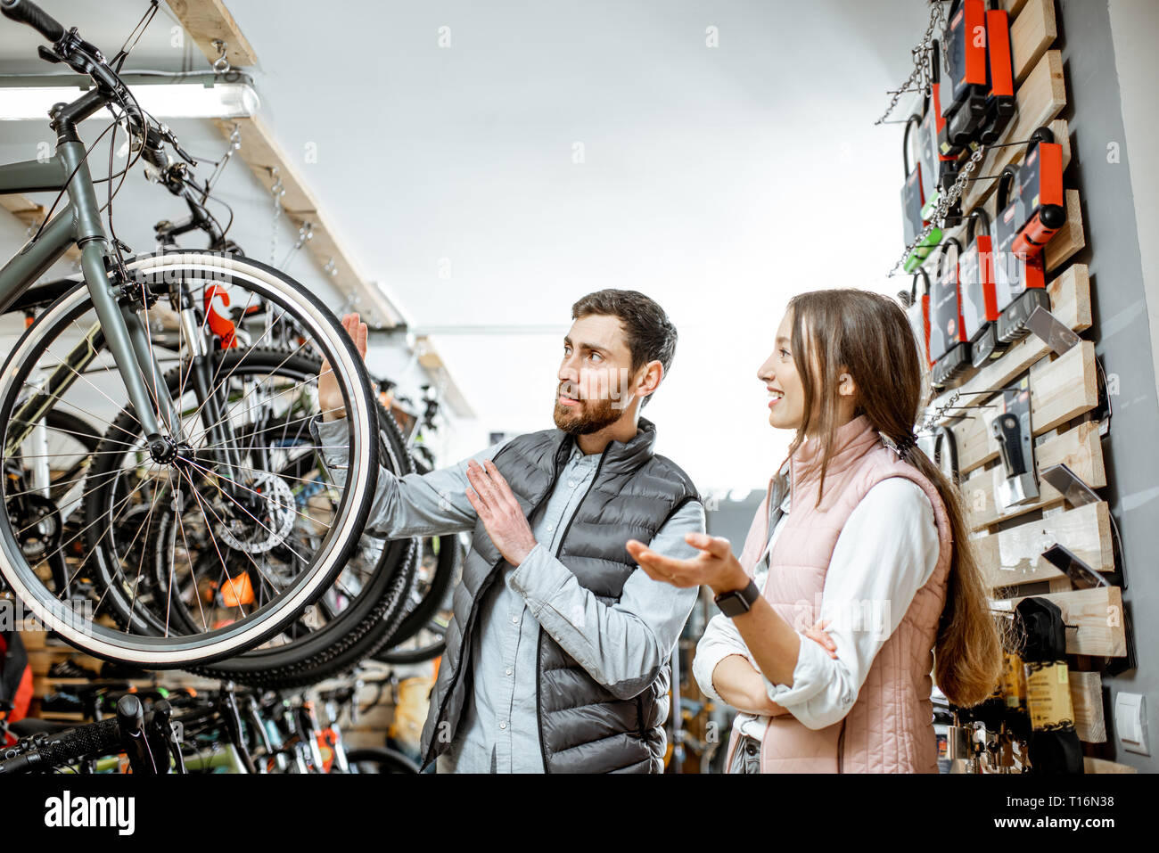 Salesman helping young woman to choose a new bicycle to buy standing in ...