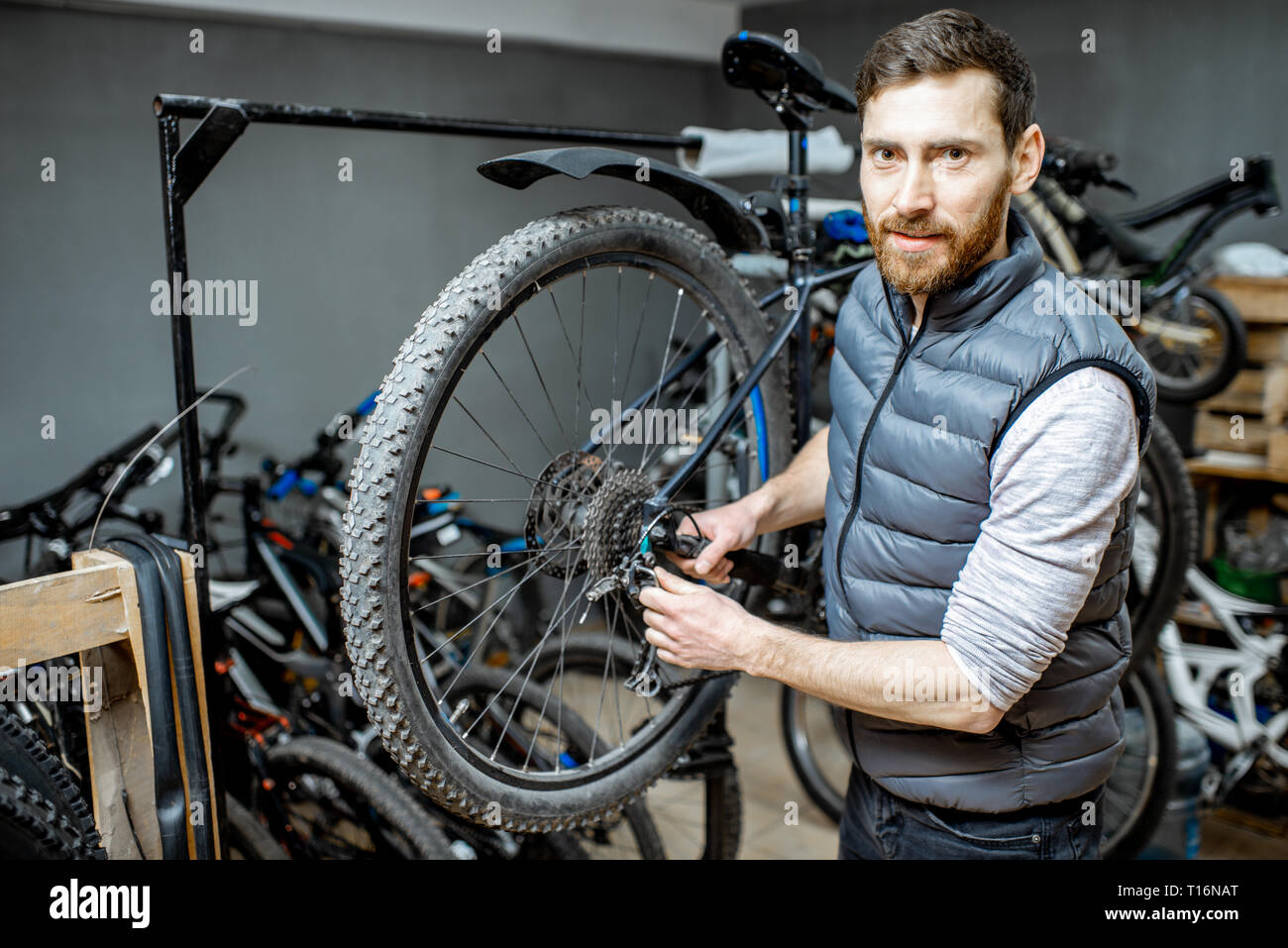 Handsome repairman serving a bicycle, fixing some malfunctions with ...