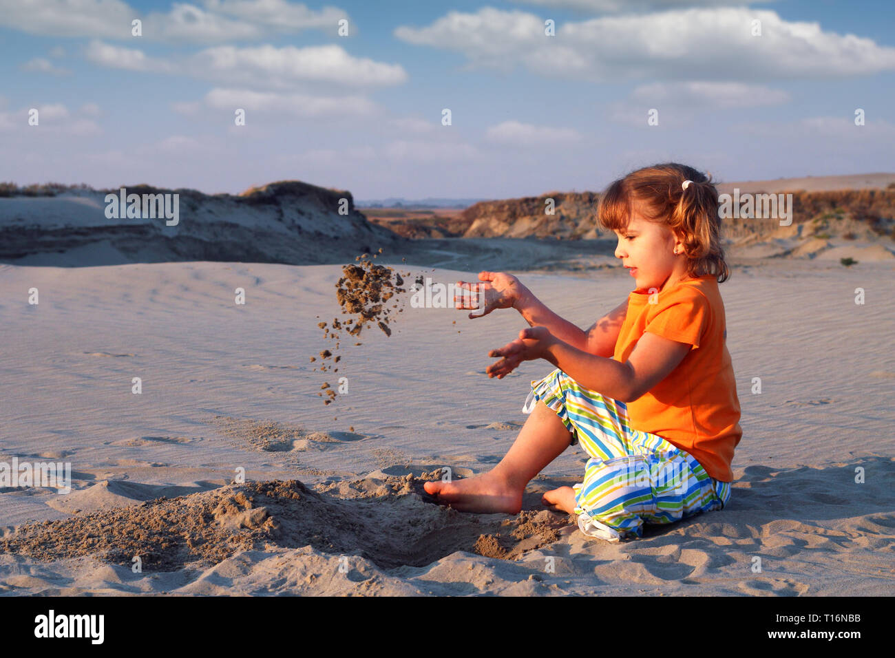 Happy little girl is playing in the sand Stock Photo - Alamy