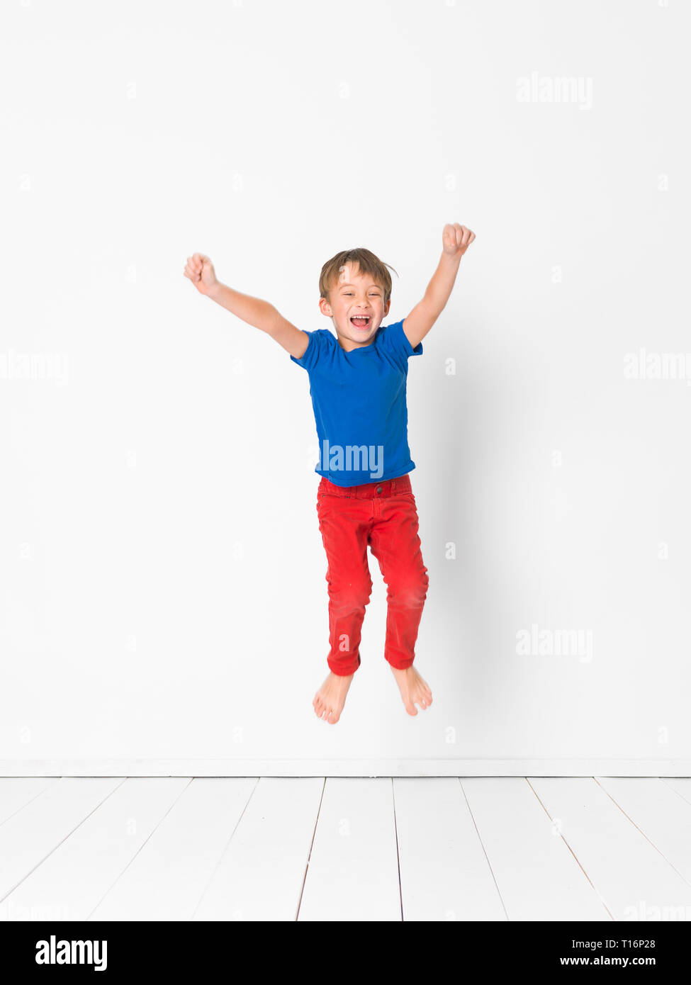 cool, cute boy with blue shirt and red trousers is jumping high in the ...