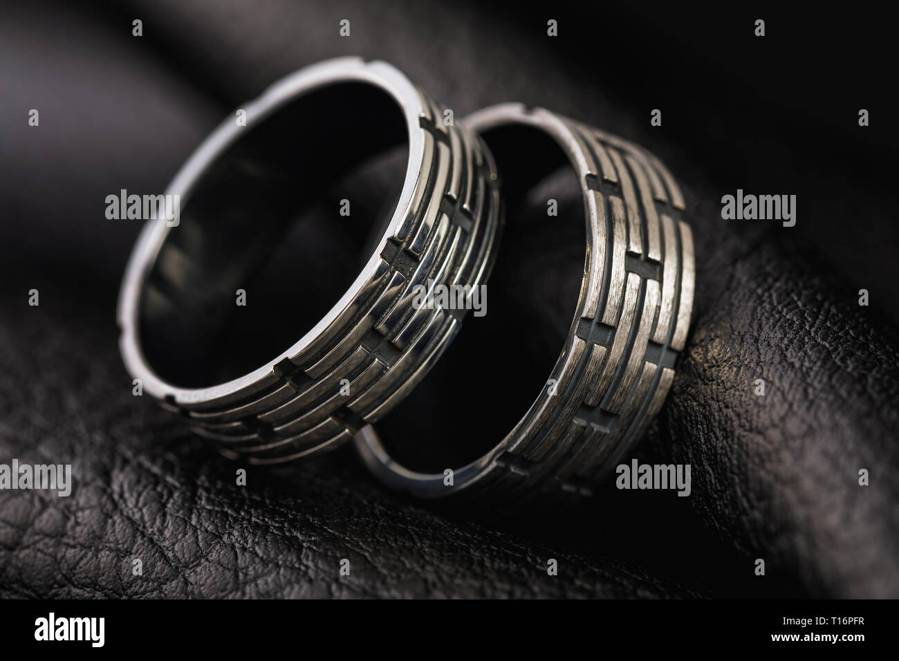 Two mens rings with different processing on a stand made of black ...