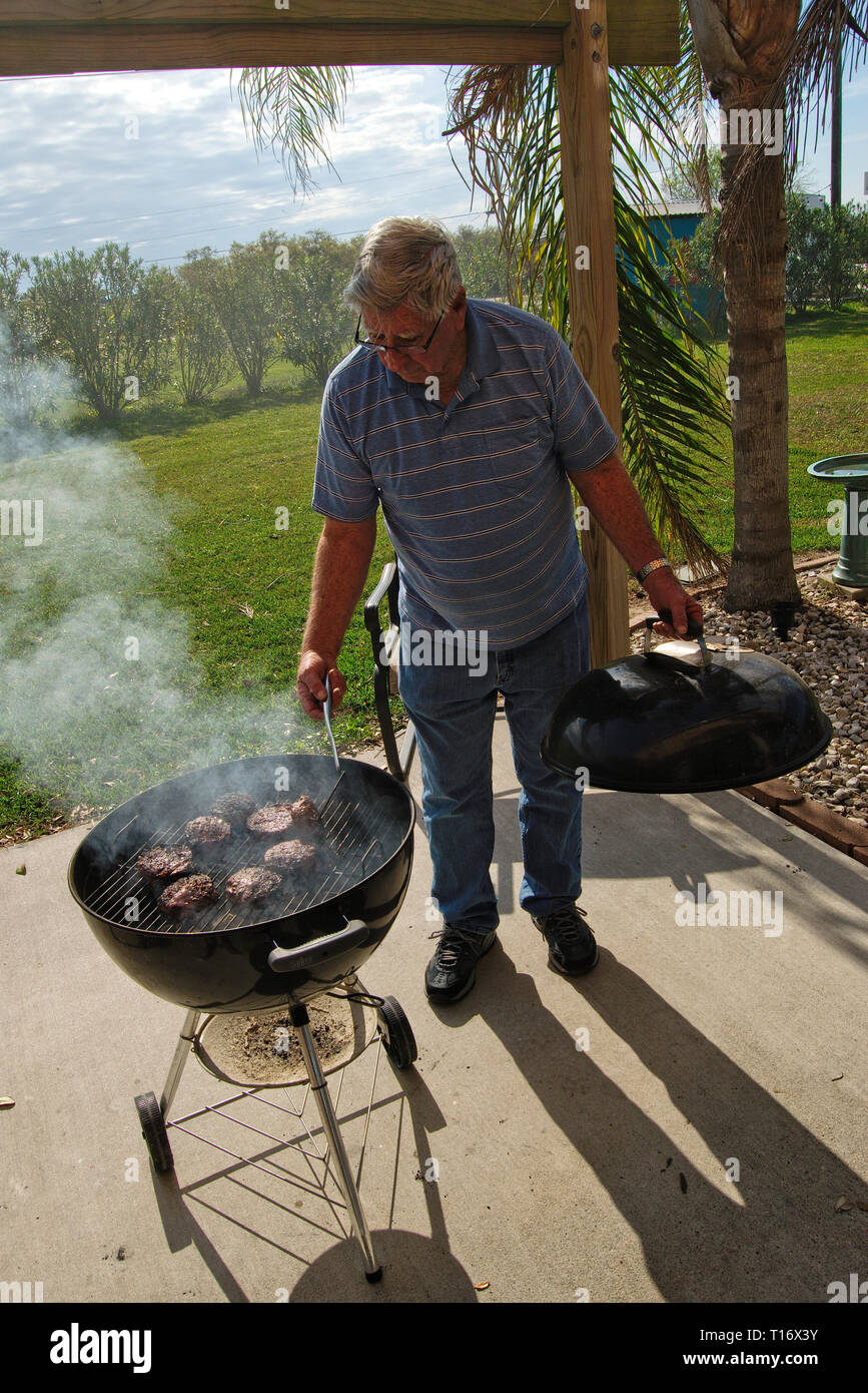 Man cooking hamburger patties on black grill Stock Photo - Alamy