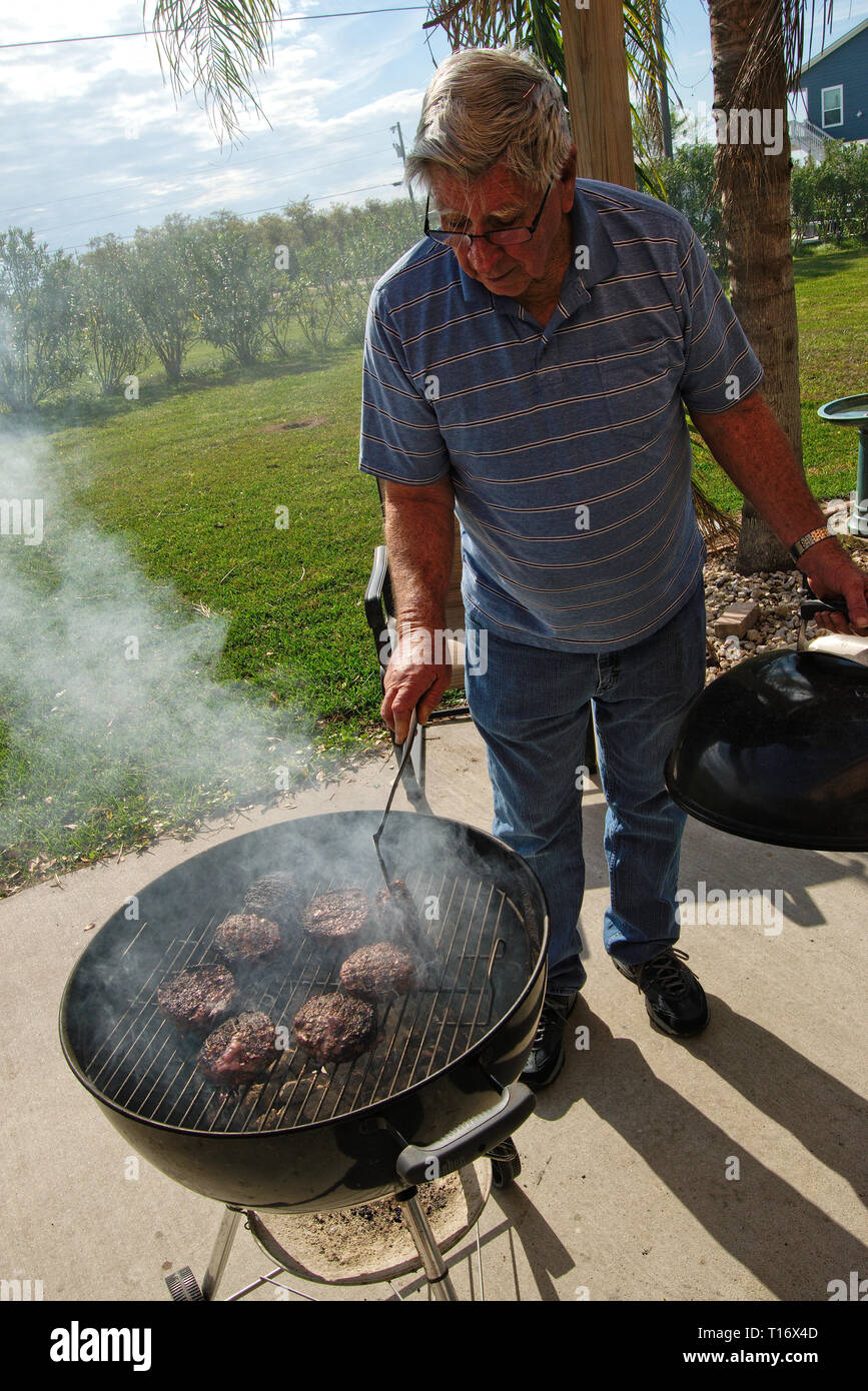 Man cooking hamburger patties on black grill Stock Photo - Alamy