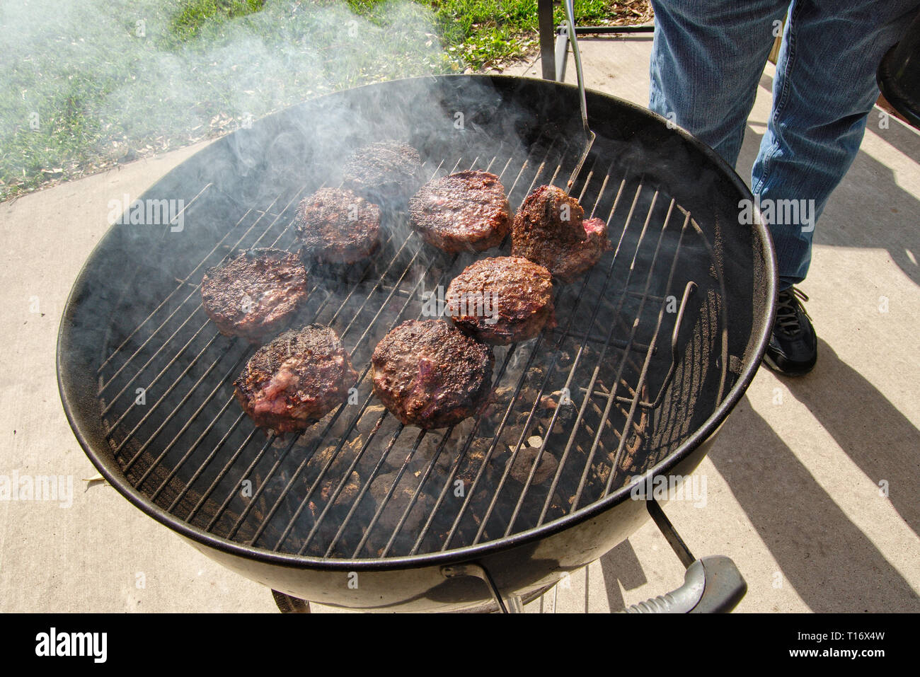 Man cooking hamburger patties on black grill Stock Photo - Alamy